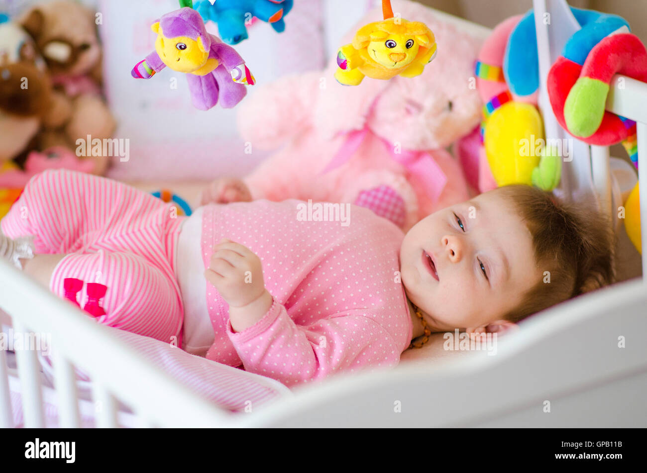 little cute baby girl playing in a cot Stock Photo - Alamy