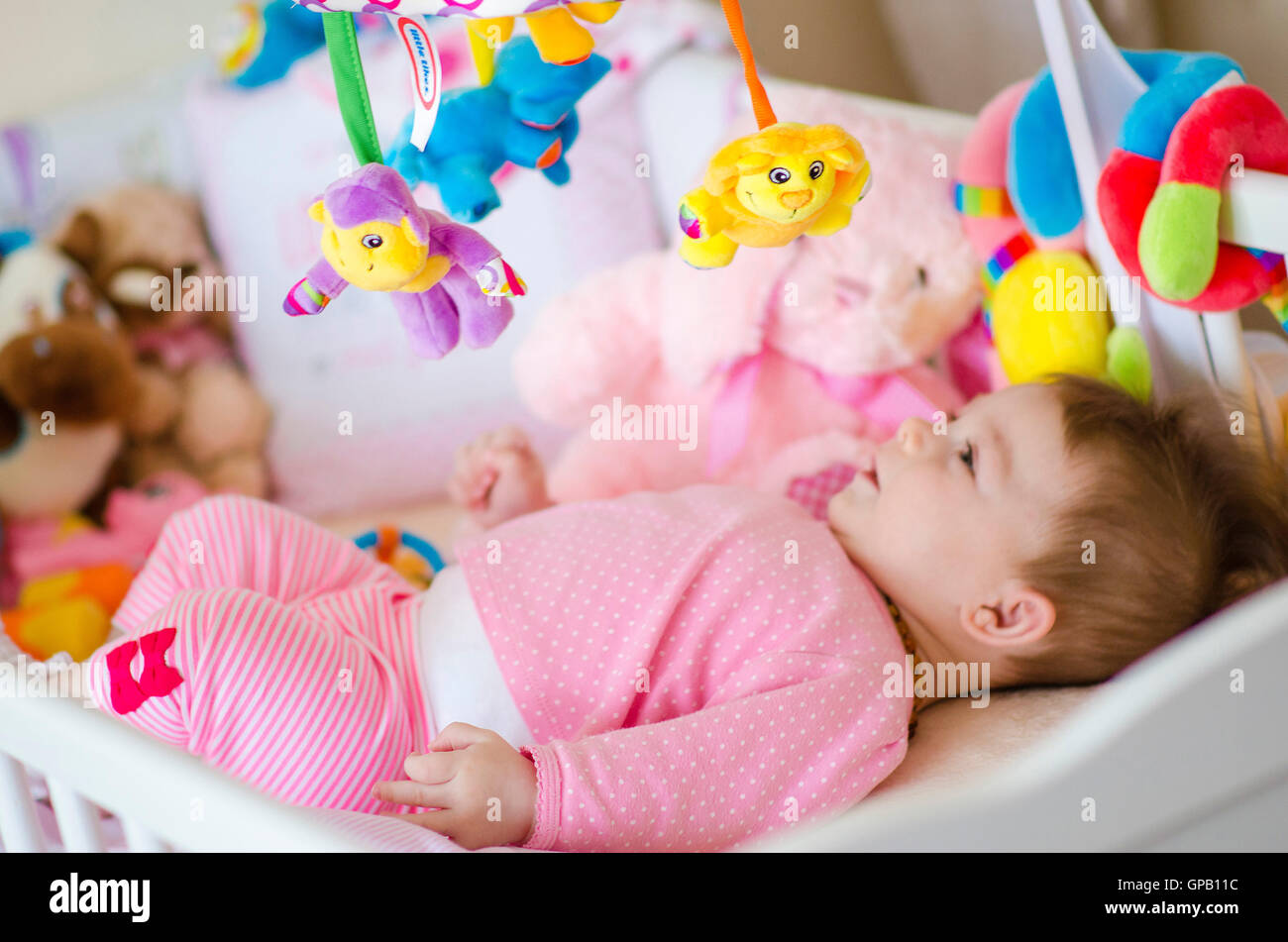 little cute baby girl playing in a cot Stock Photo - Alamy