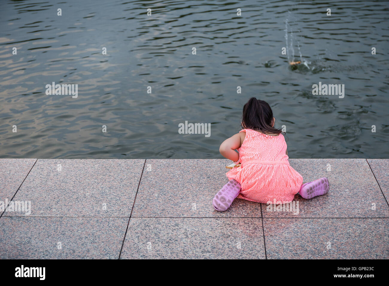 Child feeding fish in pond in evening Stock Photo - Alamy