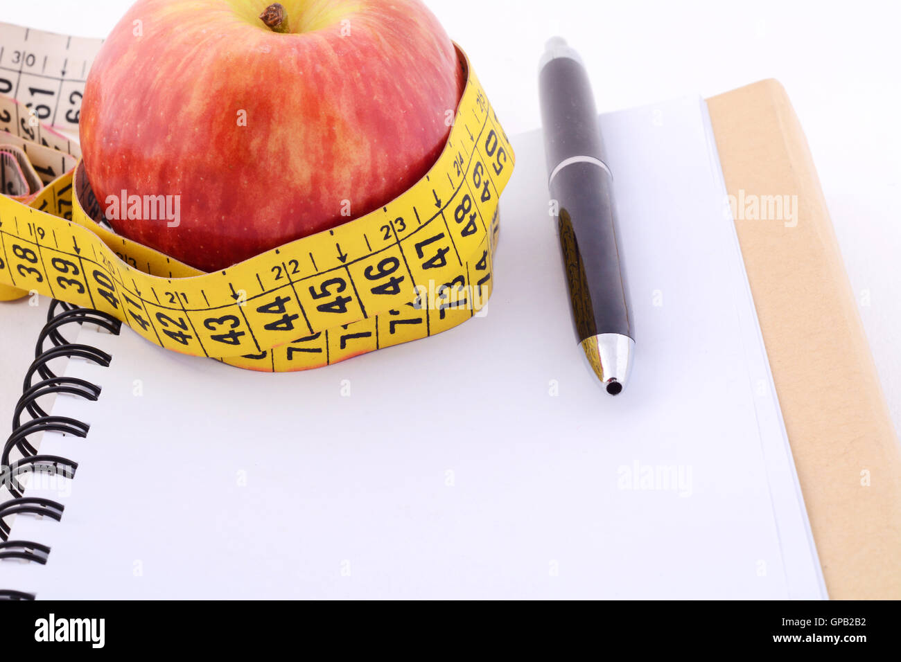An apple and measuring tape on notepad. Healthy food concept. Isolated ...