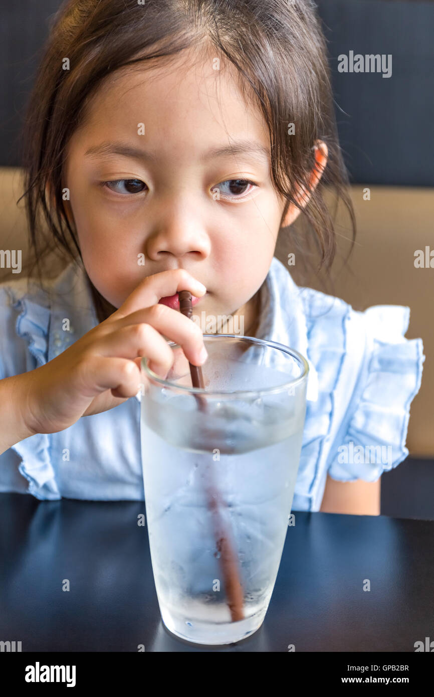 Asian Child drinking water from glass using straw Stock Photo - Alamy