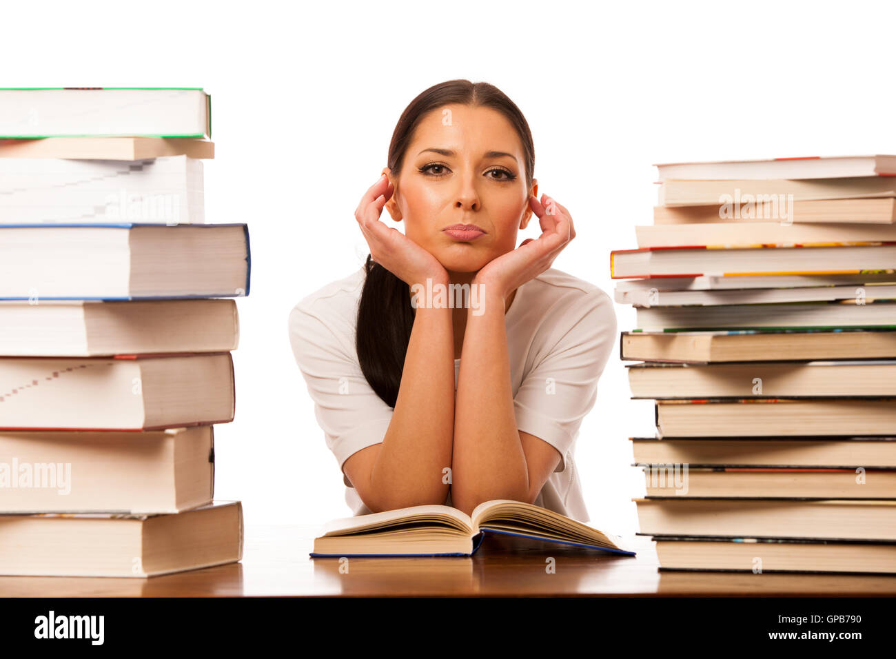 Sick and tired woman reading behind the table between two pile of books ...