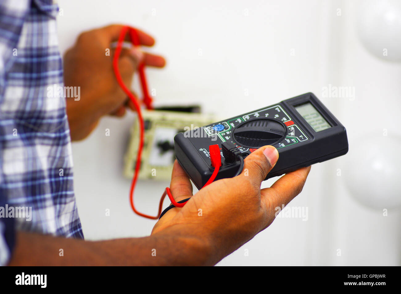 Man wearing white and blue shirt working on electrical wall socket ...