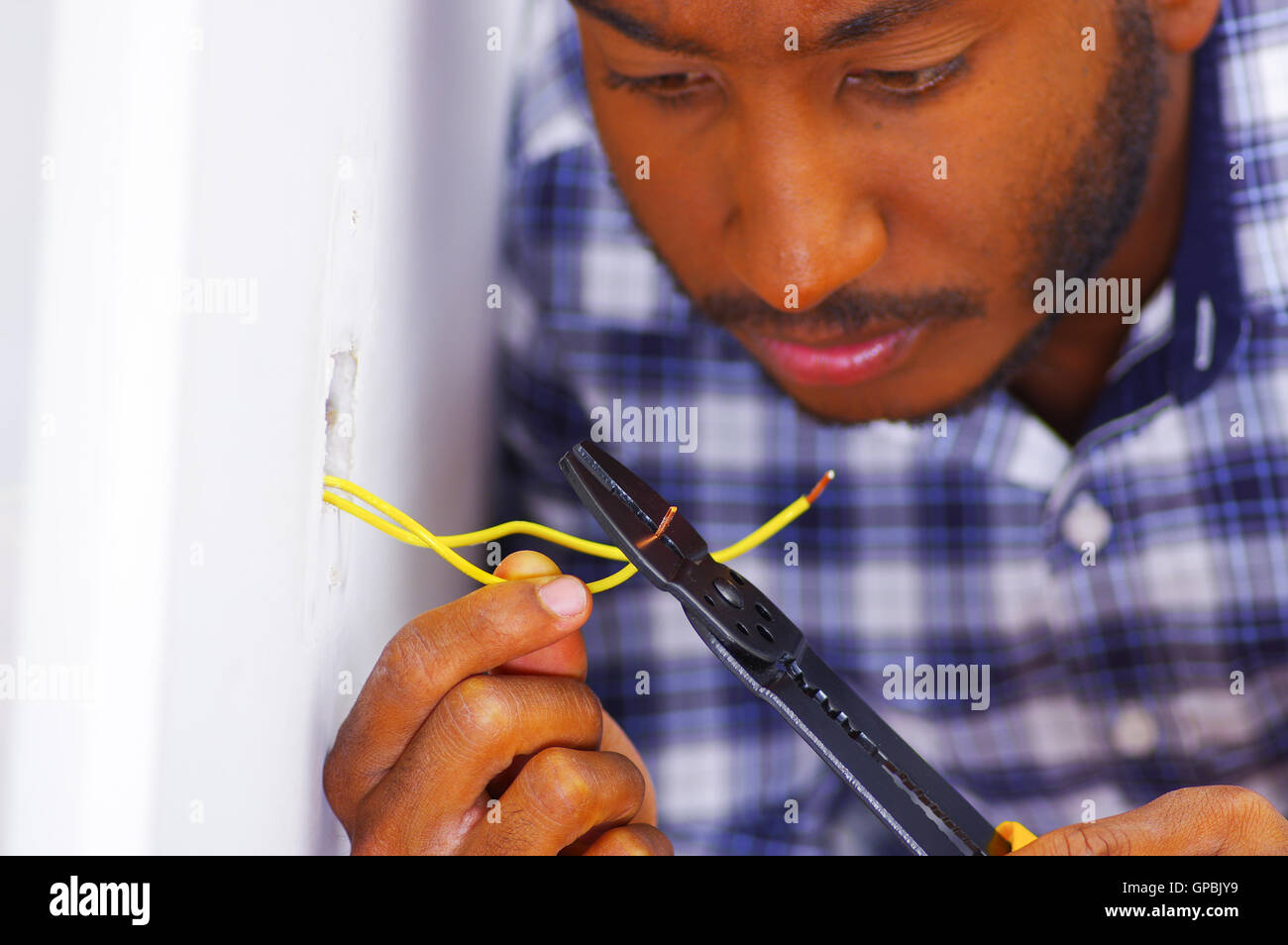 Man wearing white and blue shirt working on electrical wall socket ...
