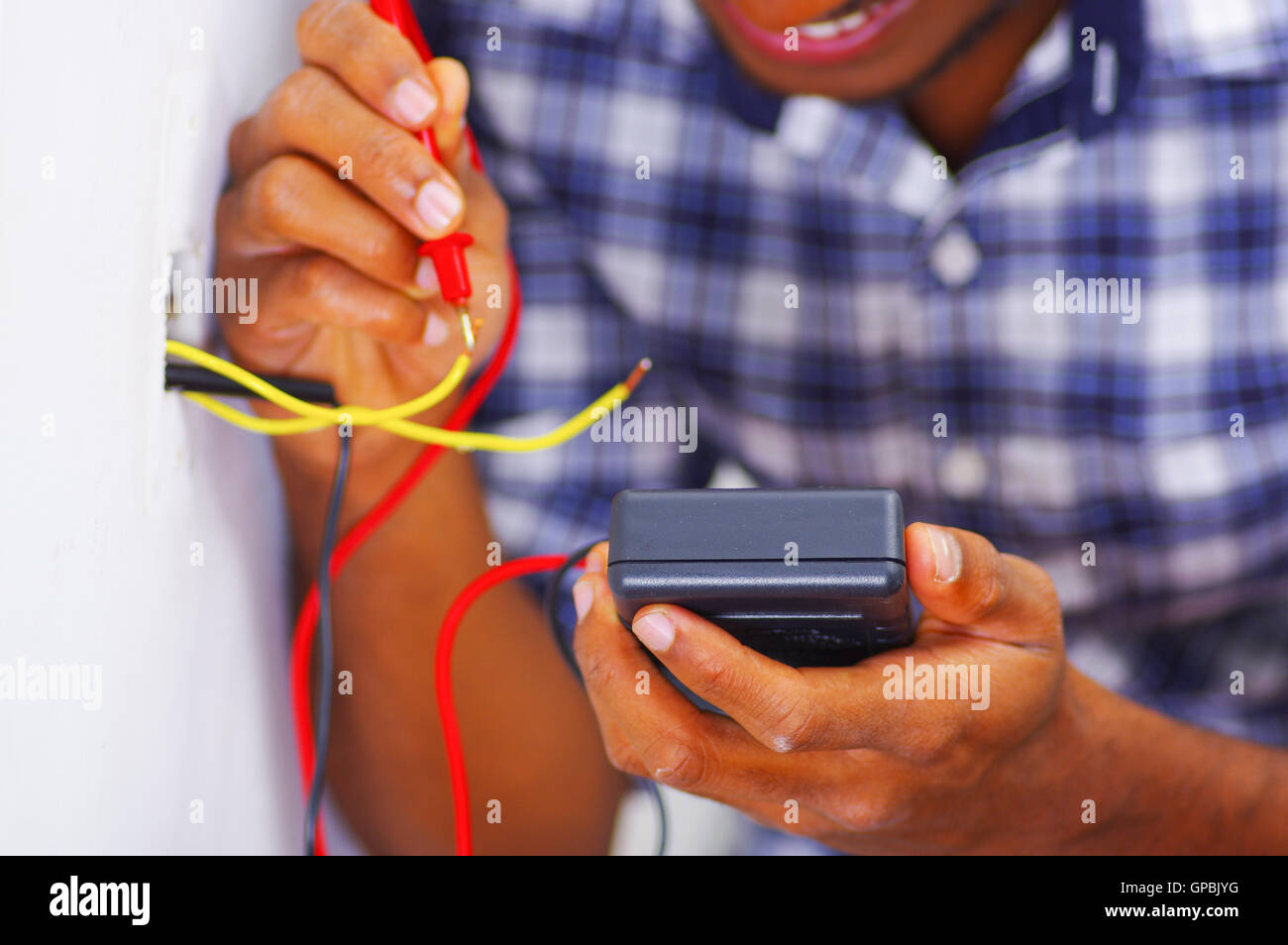 Man wearing white and blue shirt working on electrical wall socket ...