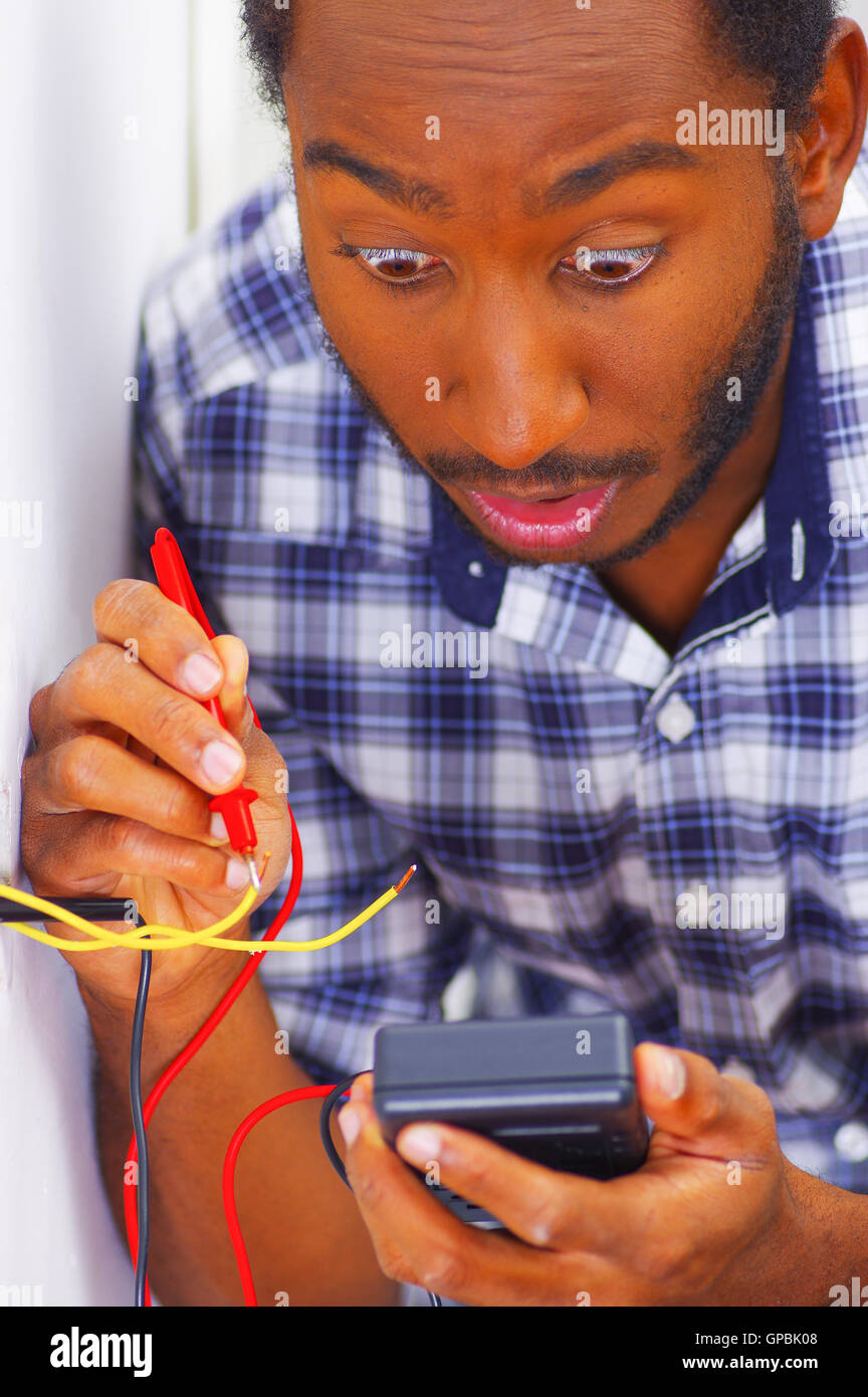 Man wearing white and blue shirt working on electrical wall socket ...