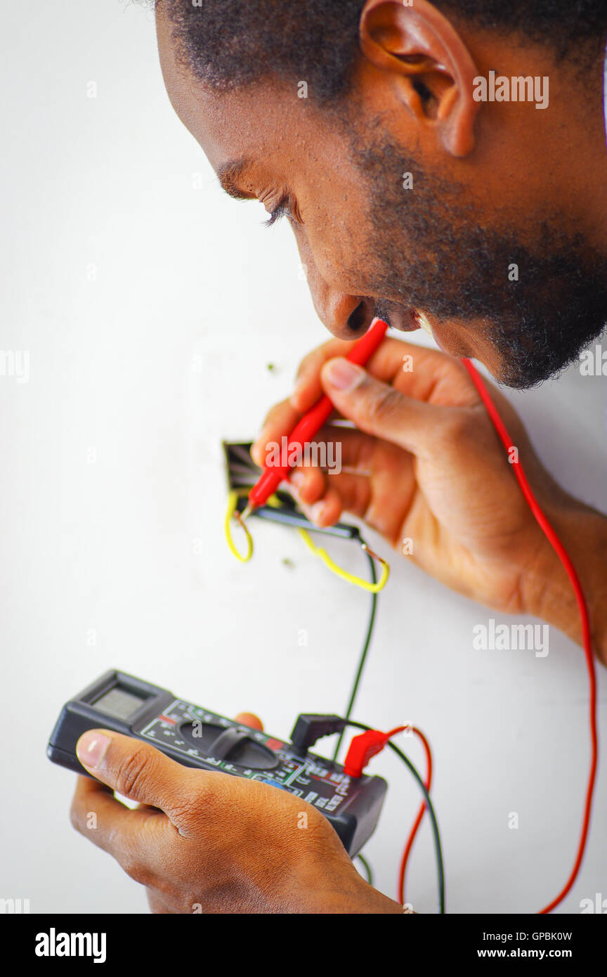 Man wearing white and blue shirt working on electrical wall socket ...