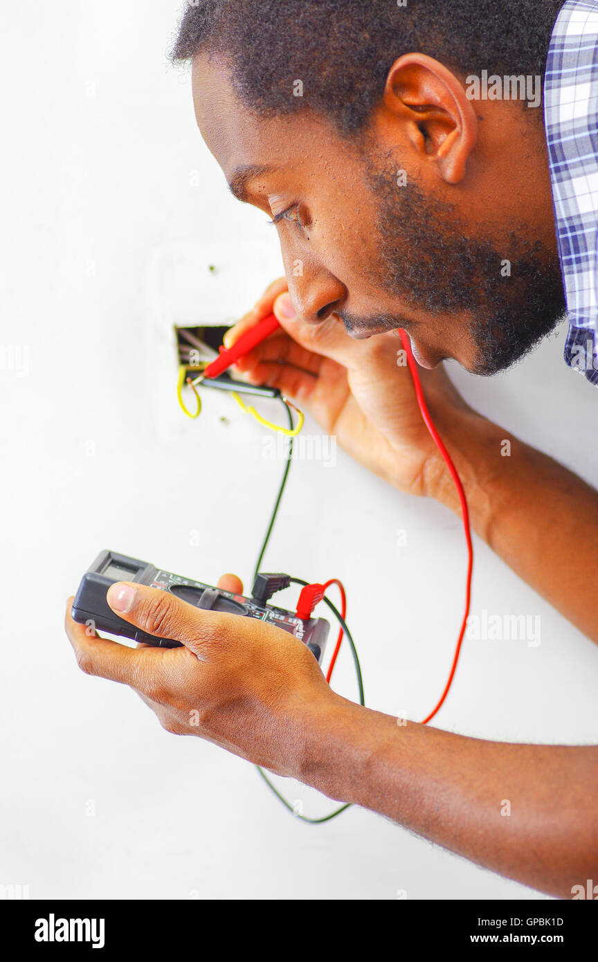 Man wearing white and blue shirt working on electrical wall socket ...