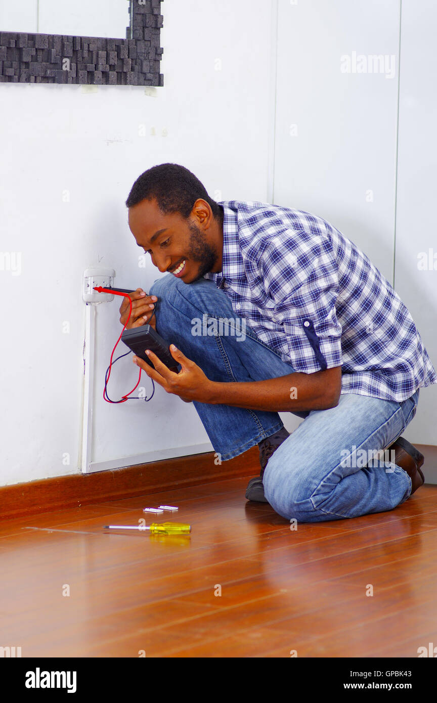 Man wearing white and blue shirt working on electrical wall socket ...