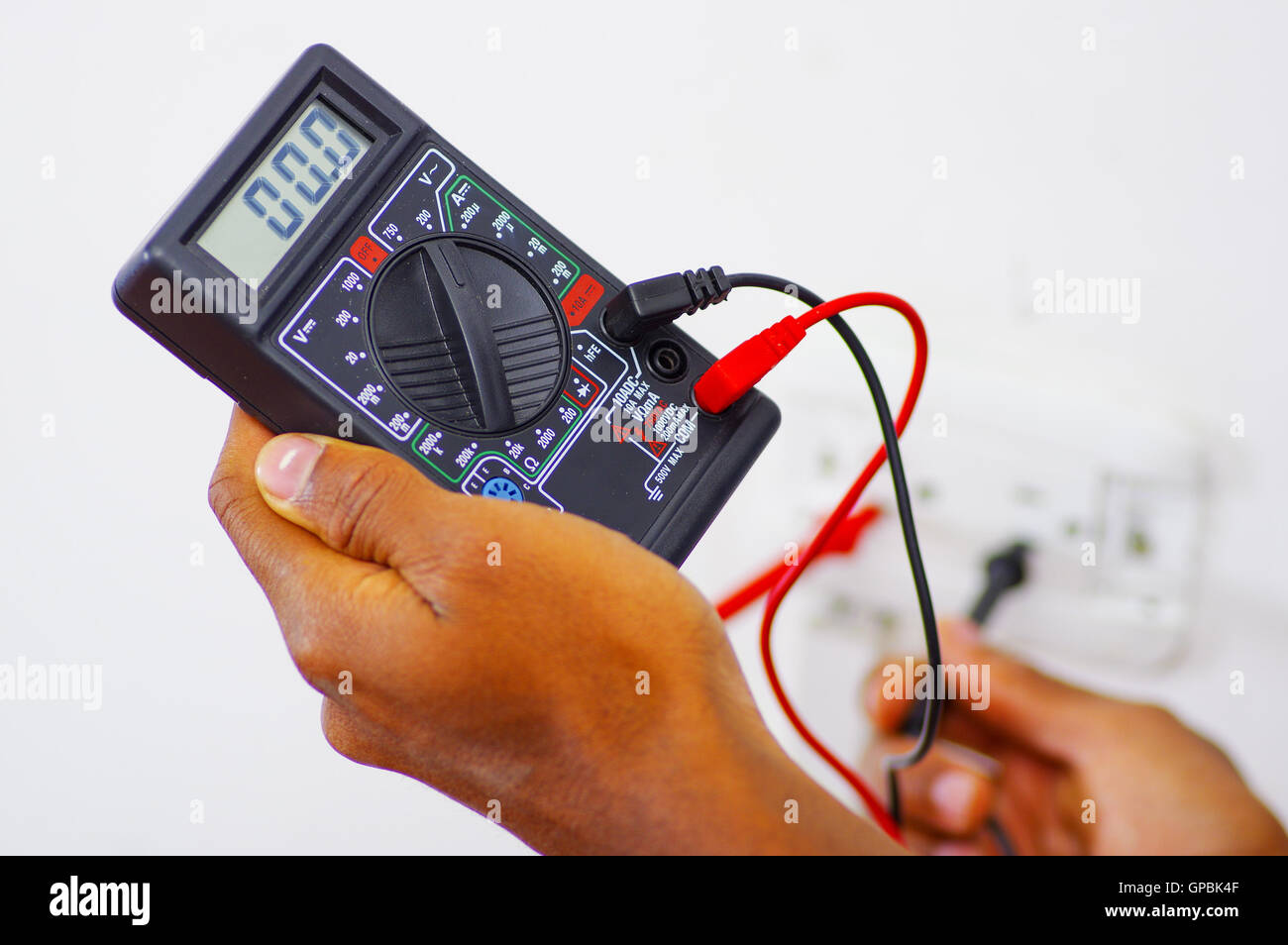 Closeup hands holding multimeter with wires connected and numbers ...