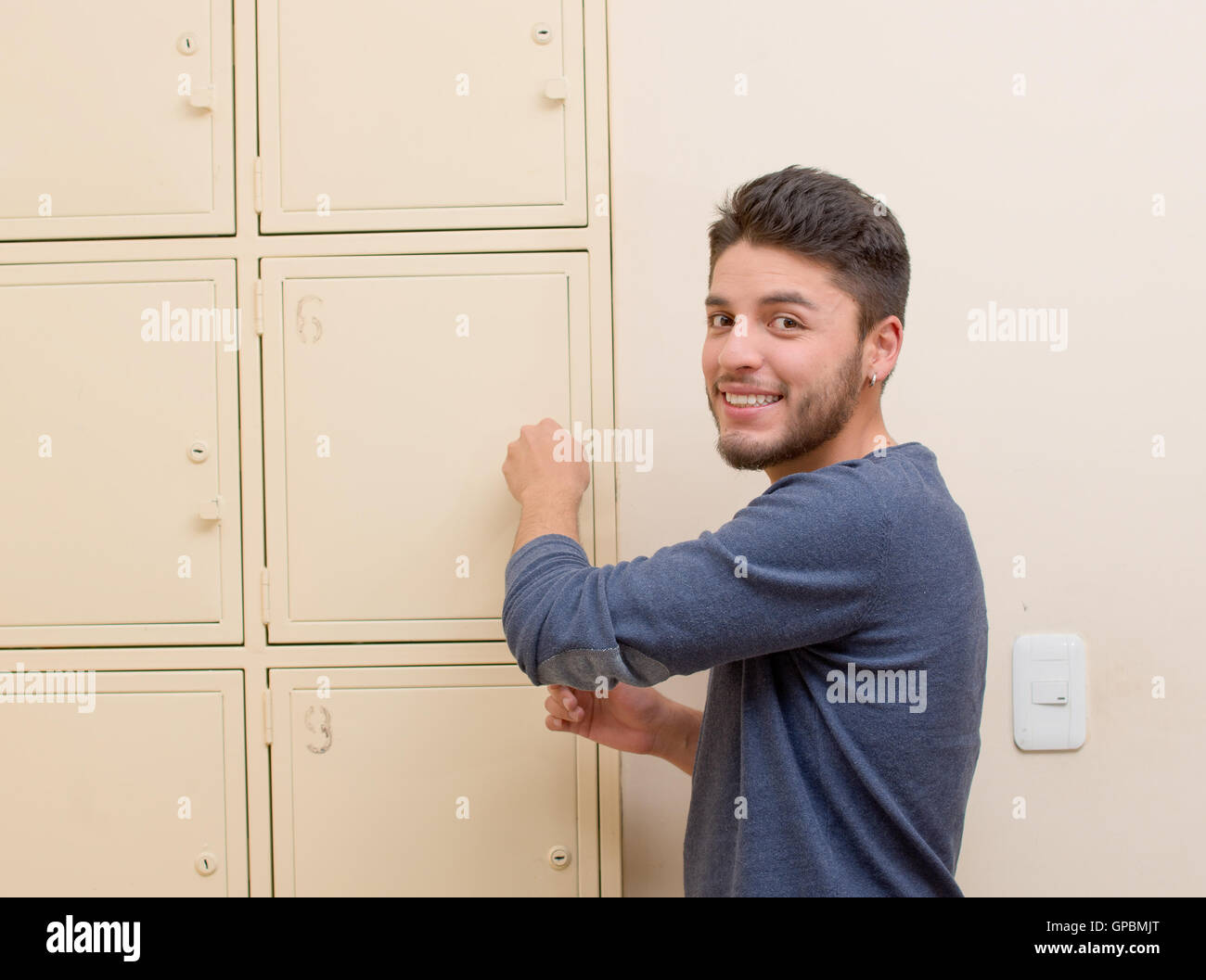 Smiling man opening locker hi-res stock photography and images - Alamy