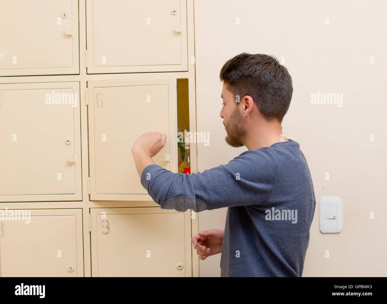 Smiling man opening locker hi-res stock photography and images - Alamy