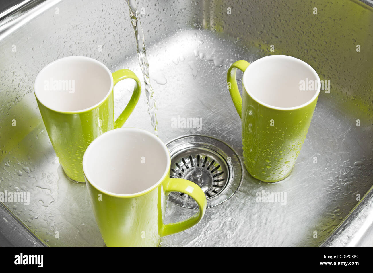 Washing green cups in the kitchen sink Stock Photo - Alamy