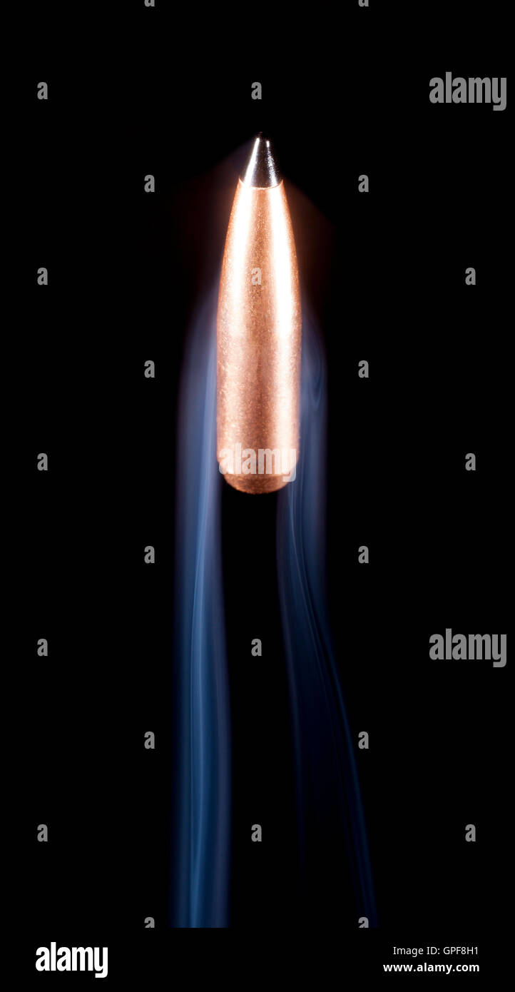Copper colored bullet with a polymer tip and smoke behind Stock Photo ...