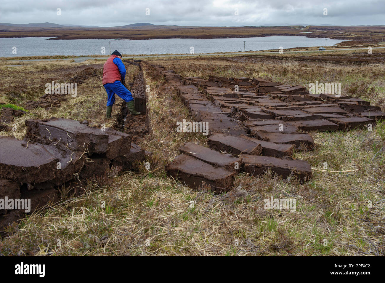 A loan Peat digger cutting peat on a hillside on the Scottish Island of ...