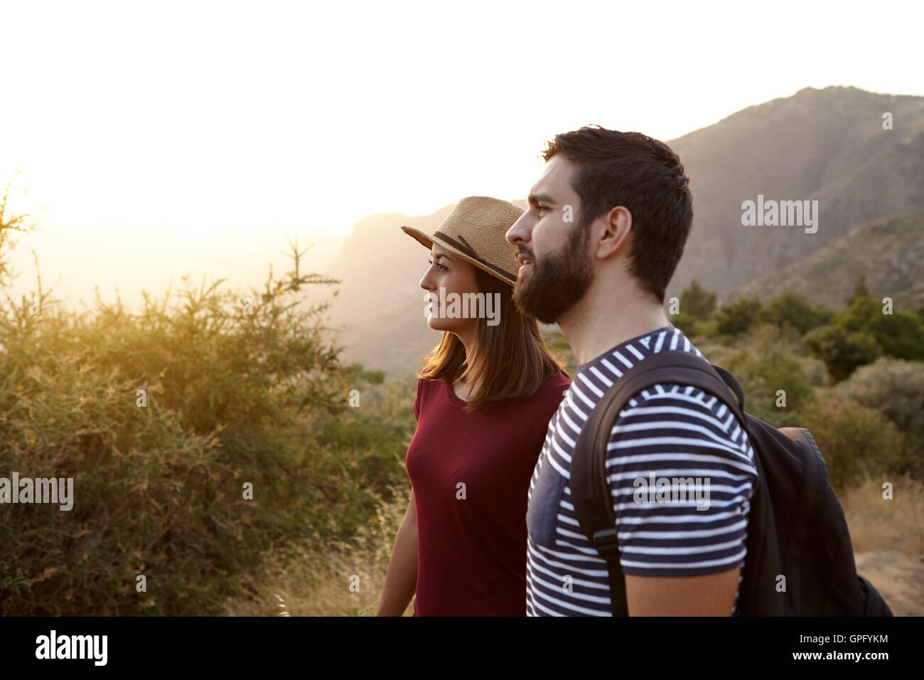 Young couple looking at something far away surrounded by bushes and ...