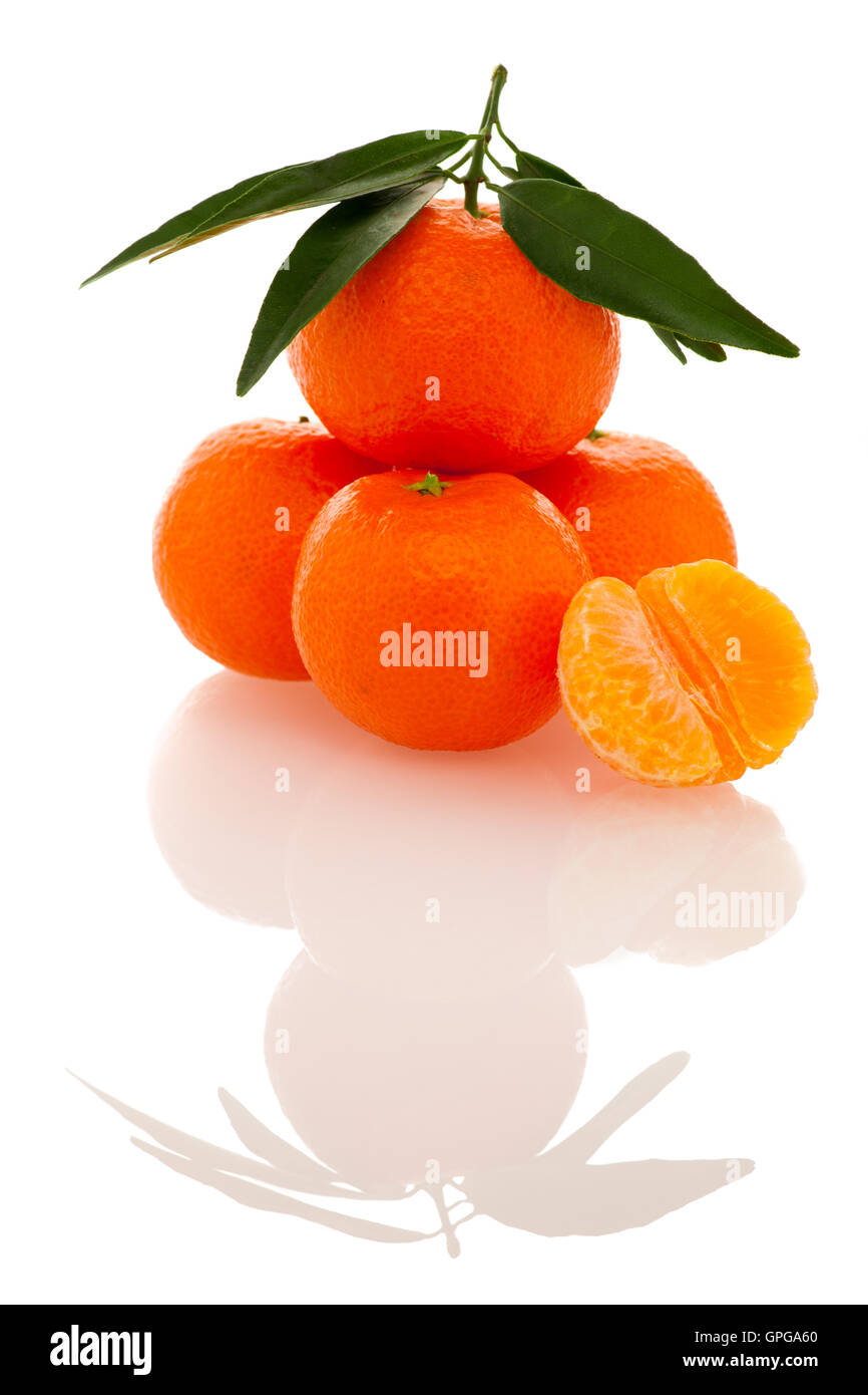 Fresh unpeeled orange mandarin citrus with green leafs and half of ...