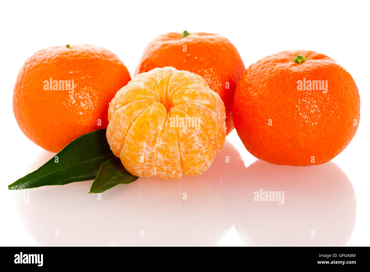 Fresh unpeeled orange mandarin citrus with green leafs and half of ...