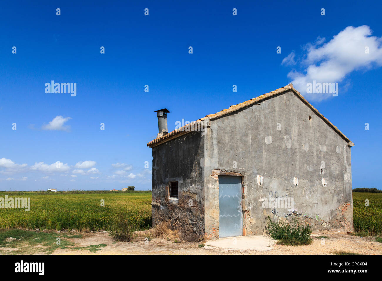 small old rendered shack with chimney by field with blue sky Stock ...