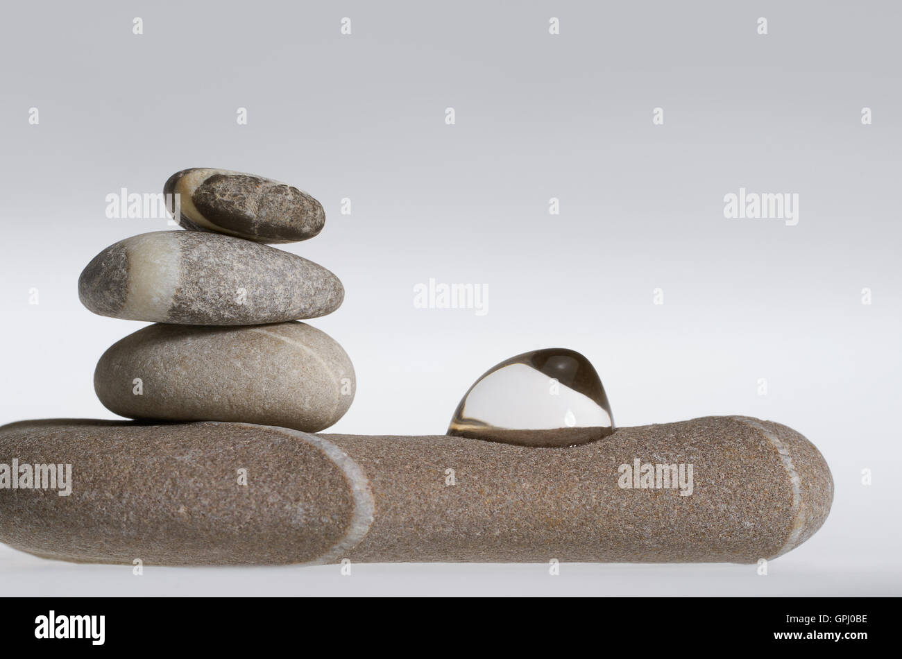stacked rounded stone pebble arrangement with fluid drop in light grey ...