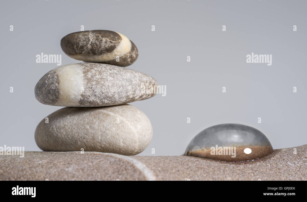 stacked rounded stone pebble arrangement with fluid drop in grey back ...
