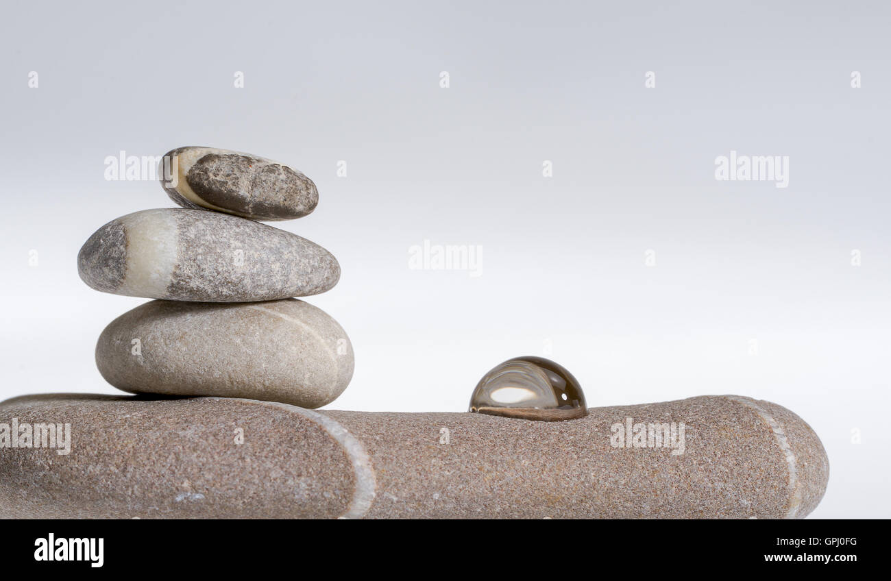 stacked rounded stone pebble arrangement with fluid drop in light grey ...