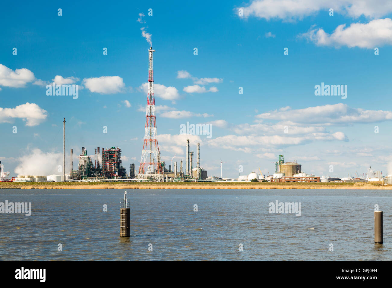 A refinery with tall flare stack in the port of Antwerp, Belgium with ...
