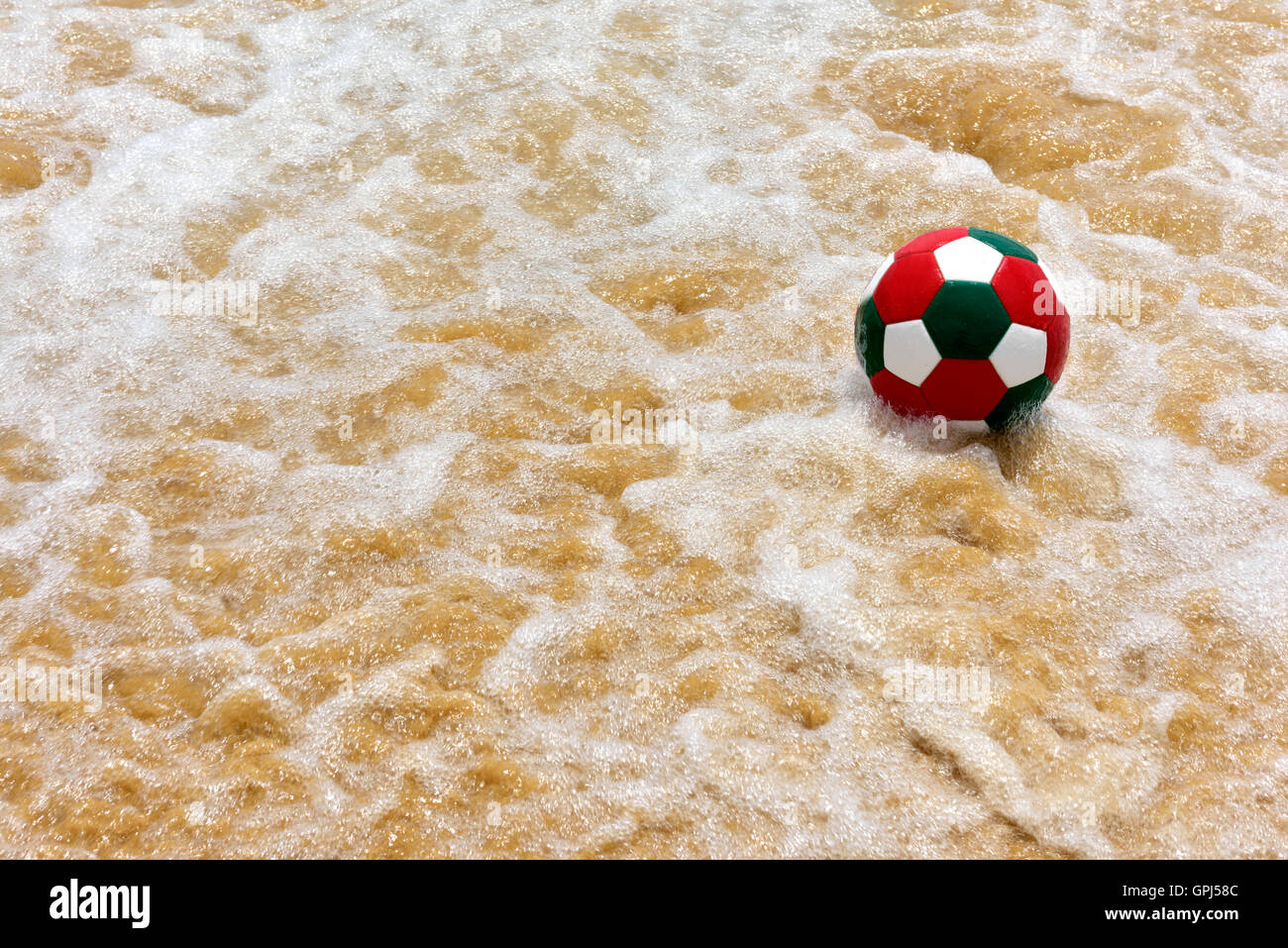 Football ball in surf on beach Stock Photo - Alamy