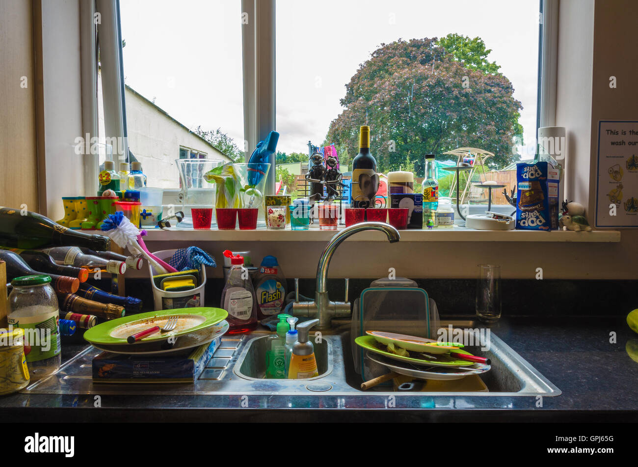 A view of a kitchen sink filled with dirty washing up and the kitchen ...