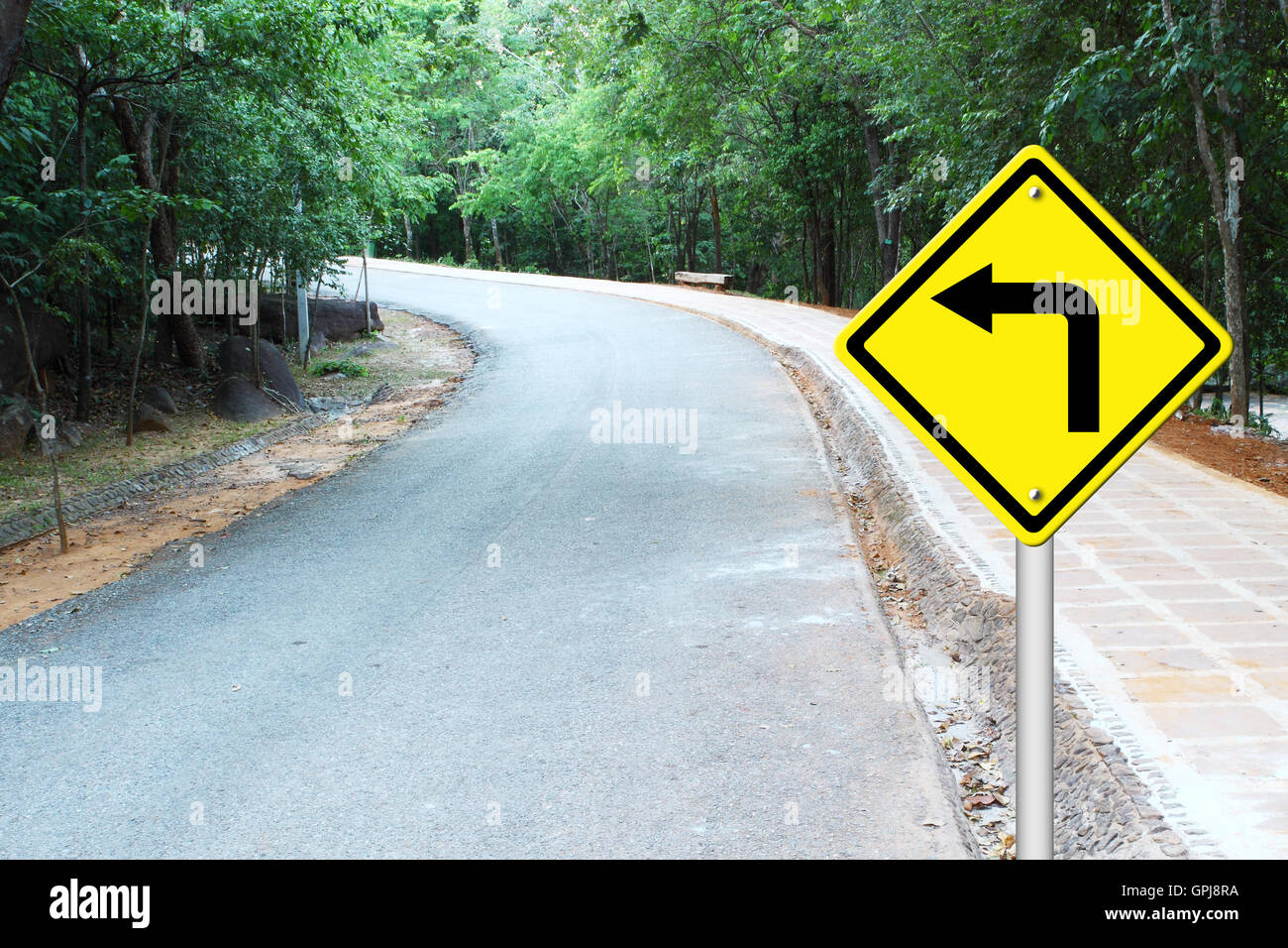 Turn left warning sign on curve road Stock Photo - Alamy