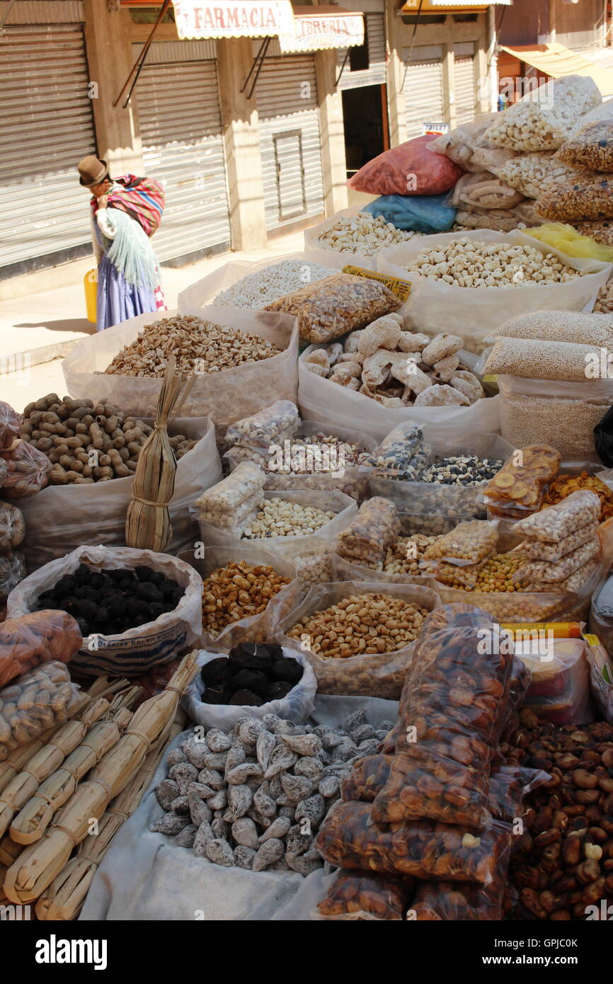 Indigenous woman walking past a market stall full of corn in Copacabana ...