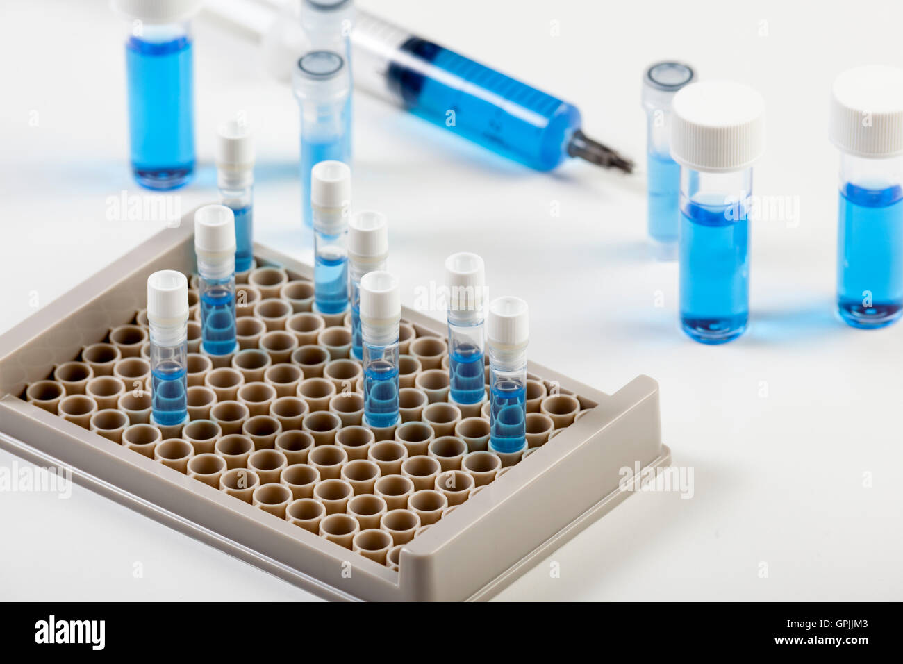 Loaded vial rack containing a blue fluid and a loaded syringe on a ...