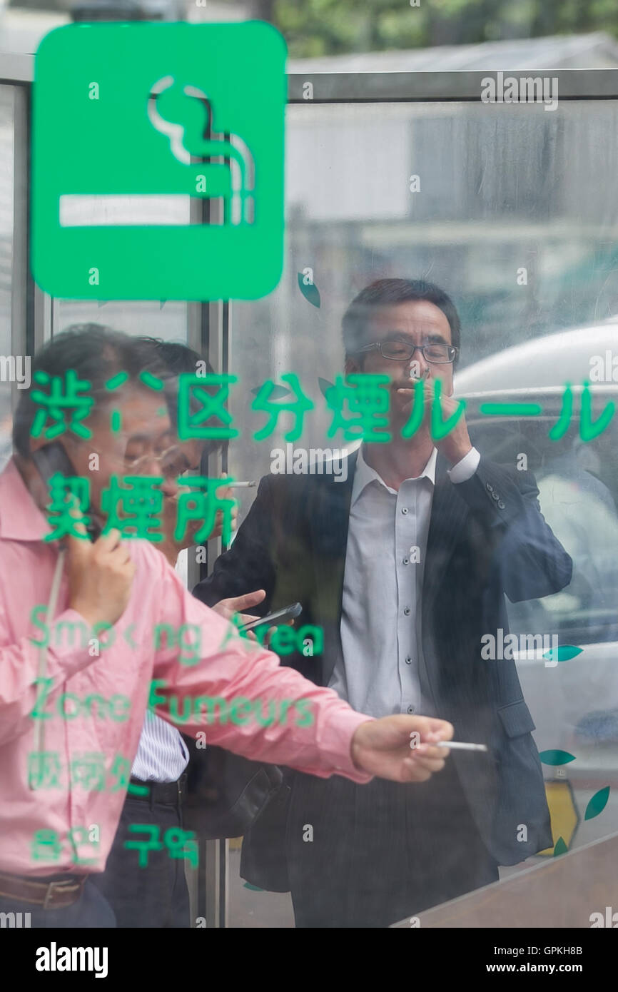People smoke in a designated smoking area outside Shibuya station on ...