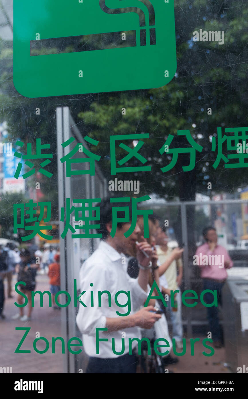 People smoke in a designated smoking area outside Shibuya station on ...
