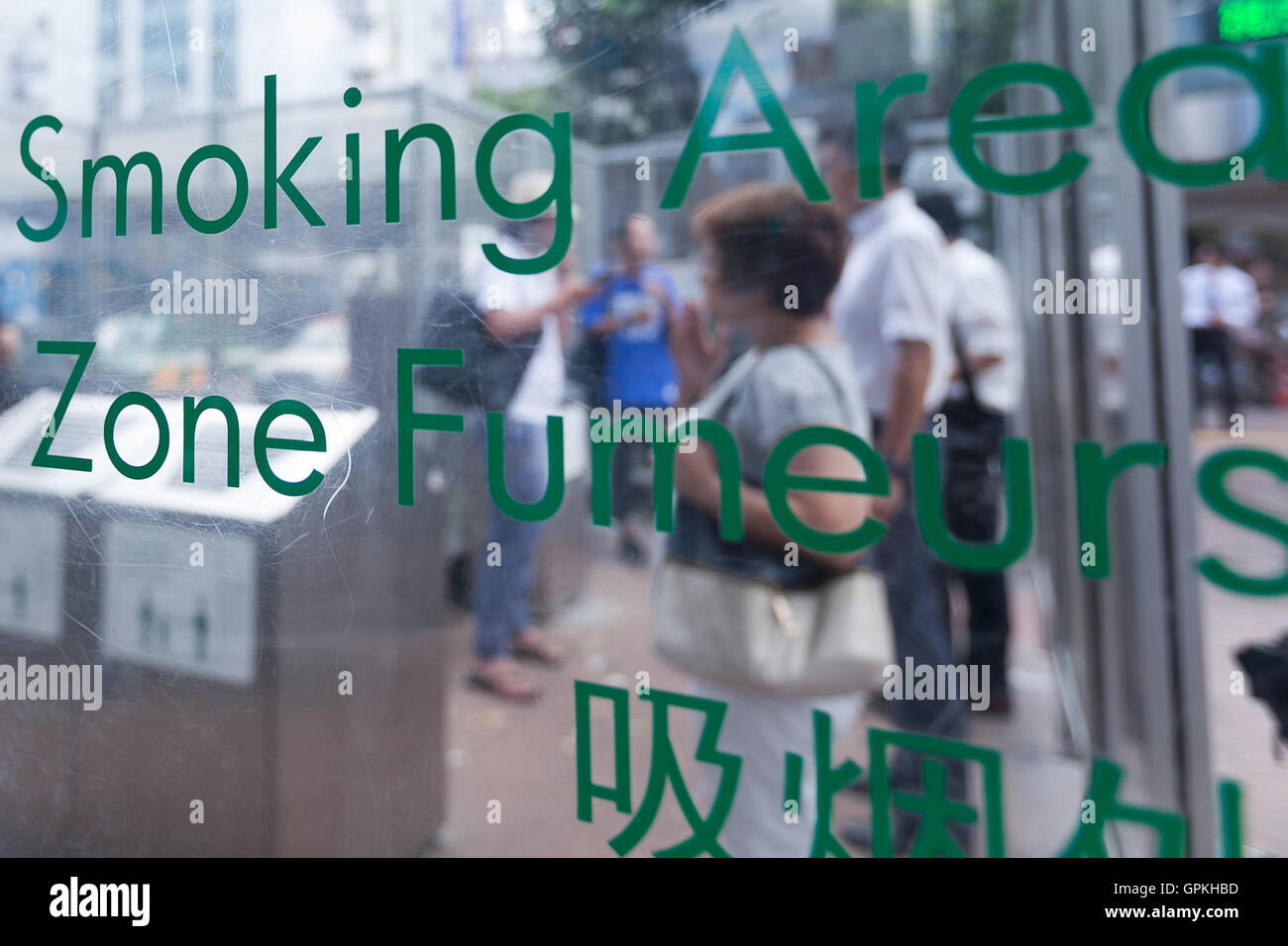 People smoke in a designated smoking area outside Shibuya station on ...