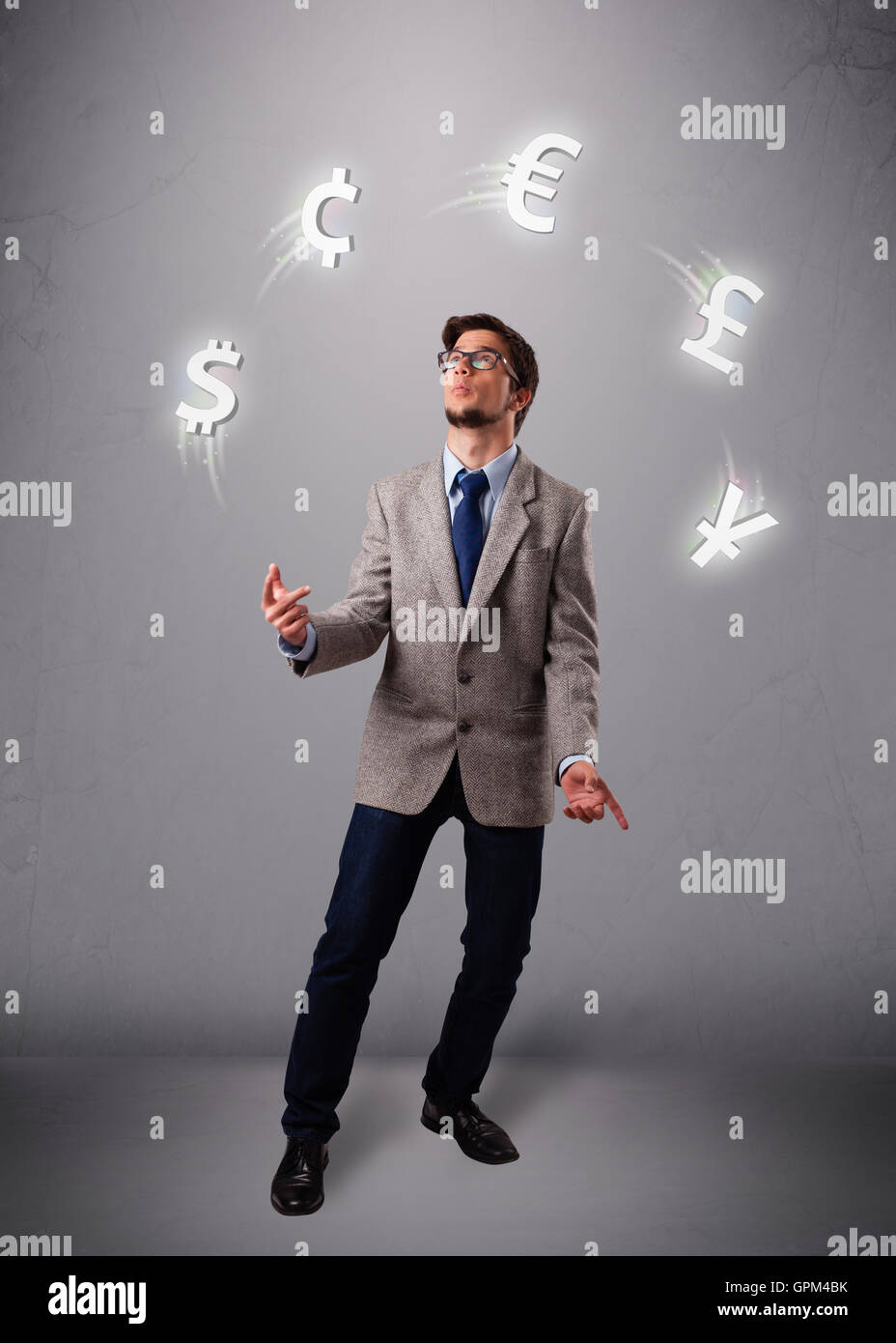 young man standing and juggling with currency icons Stock Photo - Alamy