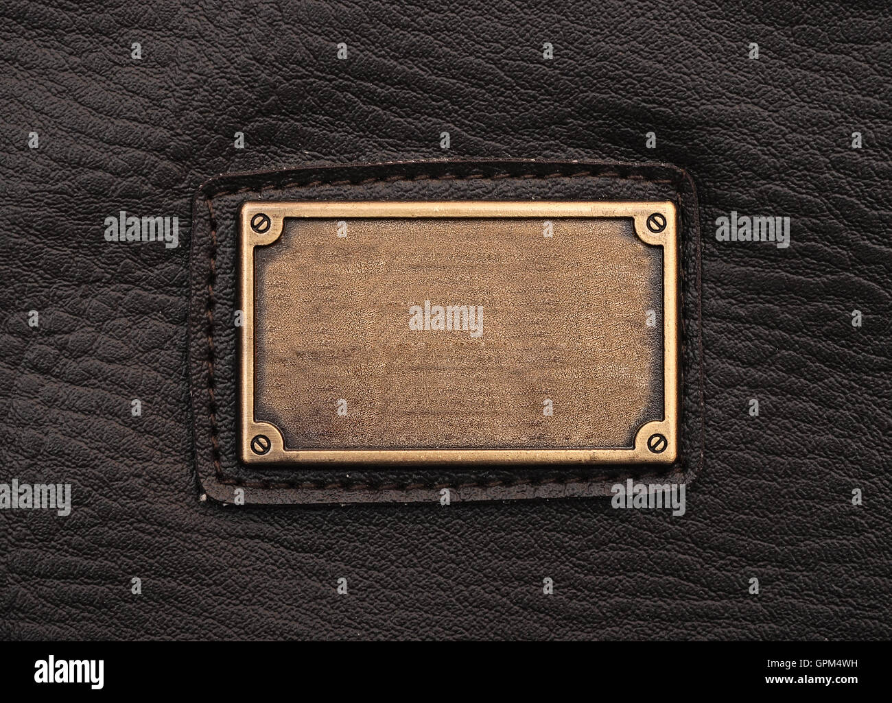 metal label on old black leather background Stock Photo - Alamy