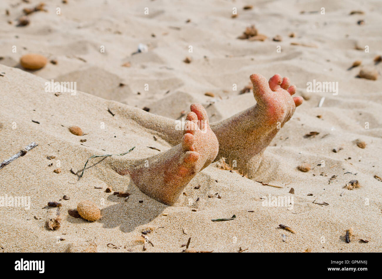 two feet on the beach in rigor mortis protrude from the sand Stock ...