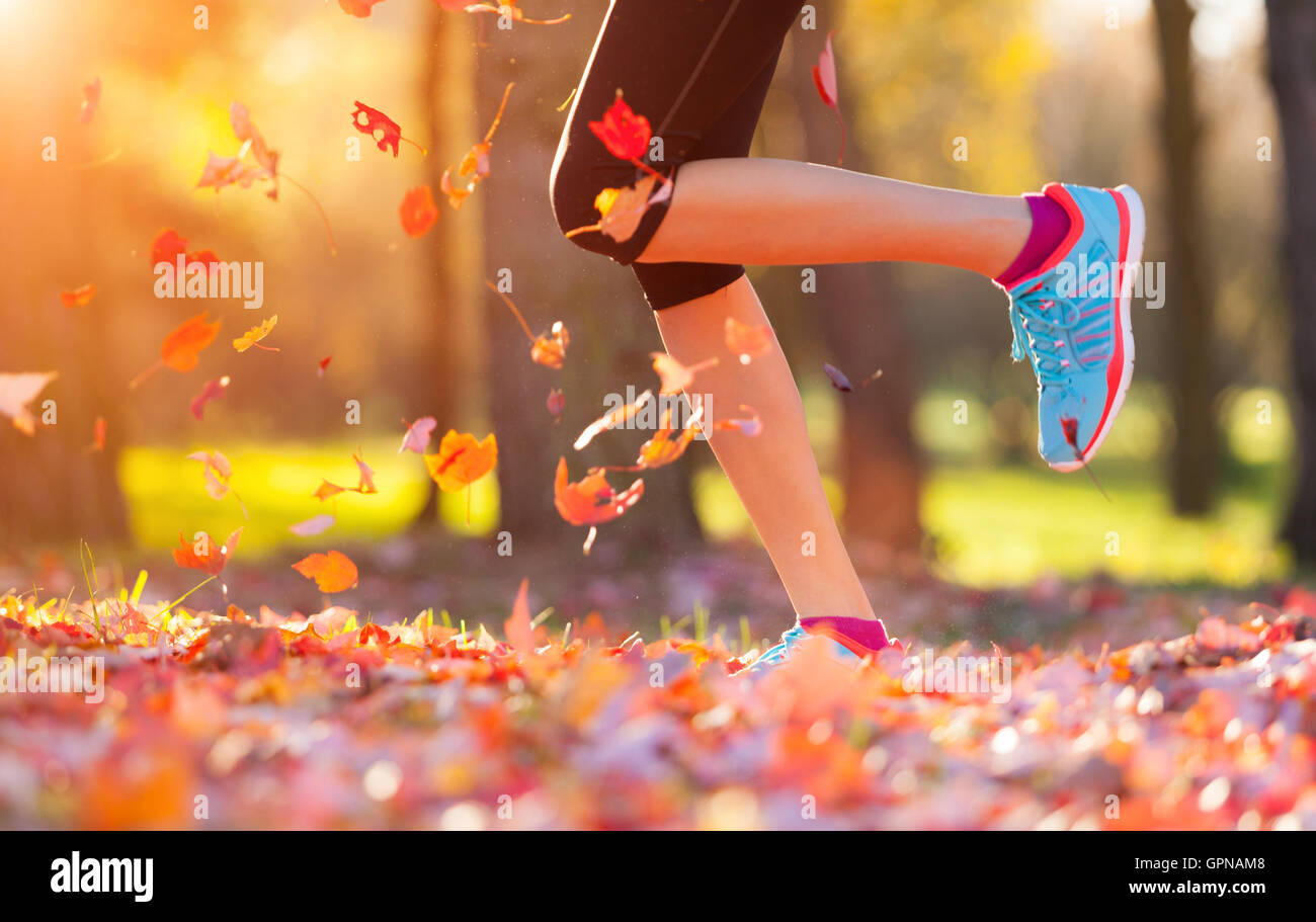 Close up of feet of woman runner running in autumn leaves, concept of ...