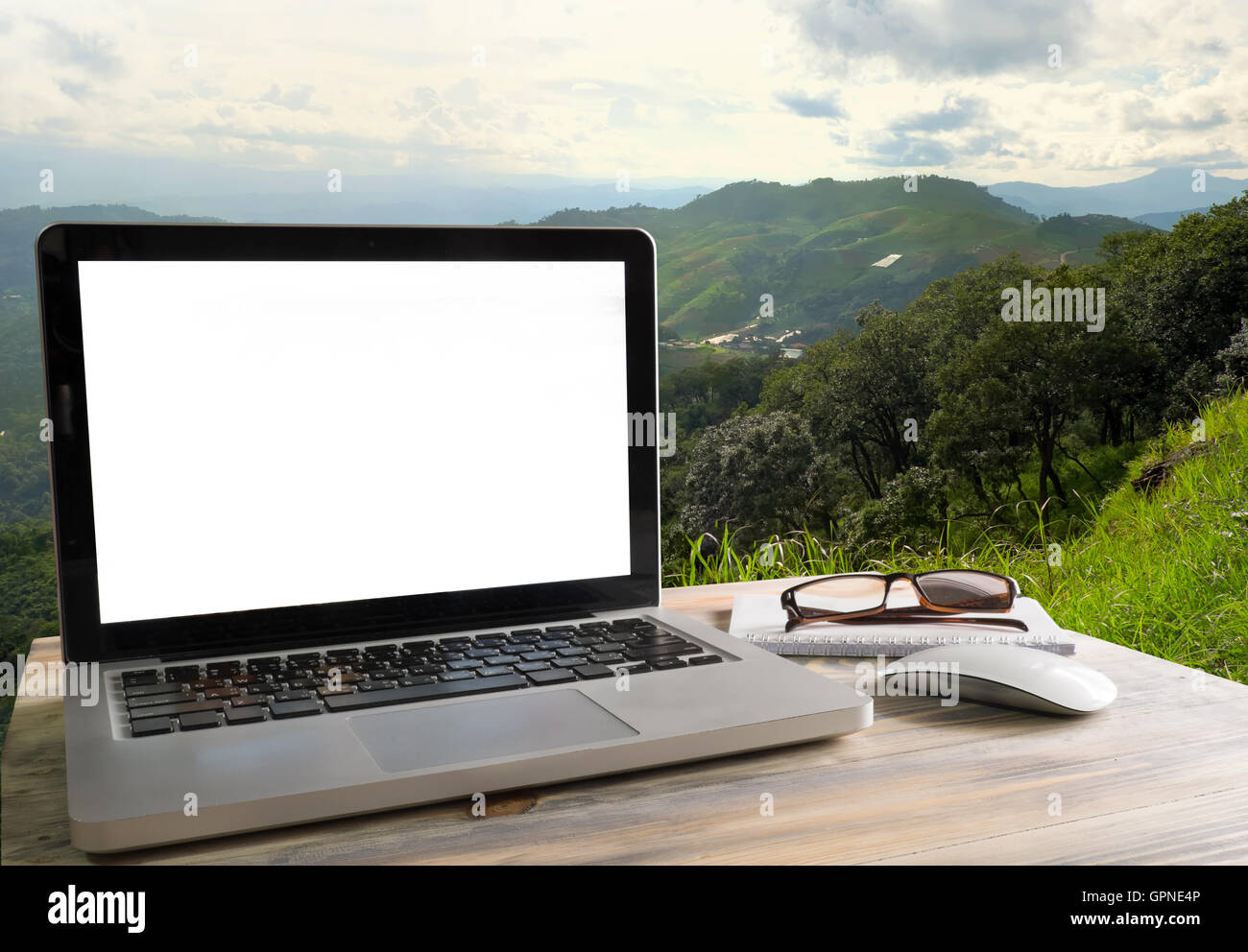 laptop over wooden table outdoors and blurred background of trees in ...
