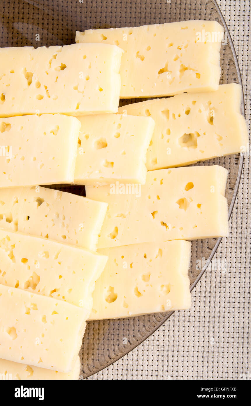 Group slices dry hard yellow cheese on a plate closeup on fabric ...