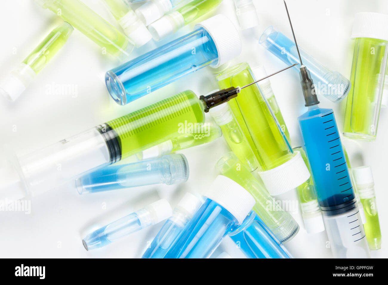 Syringe's and vials loaded with green and blue fluids on a white ...