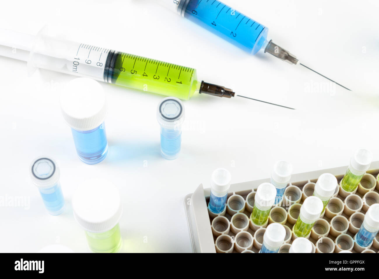 Two loaded syringe's and a vial rack containing bule and green samples ...