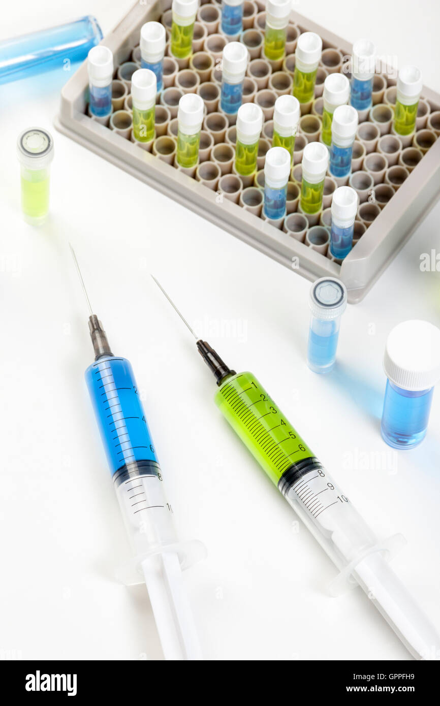 Two loaded syringe's filled with green and blue fluids on a white ...
