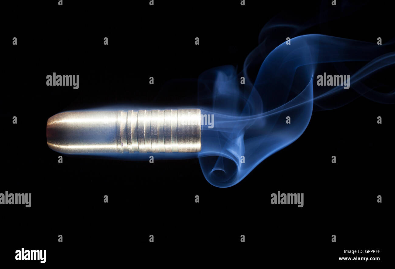 Copper colored bullet with smoke behind on a black background Stock ...