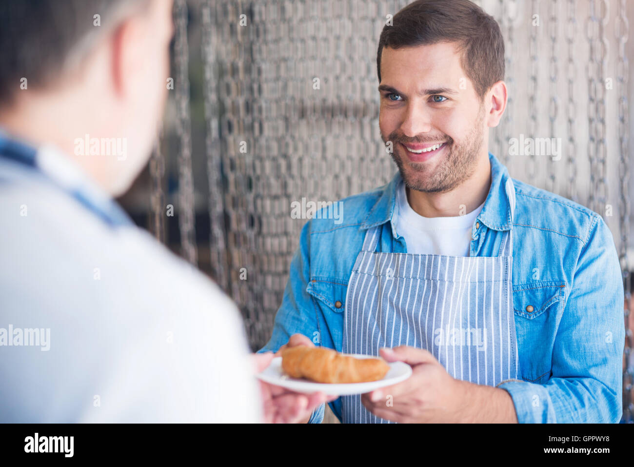 Positive baker holding plate with croissant Stock Photo - Alamy