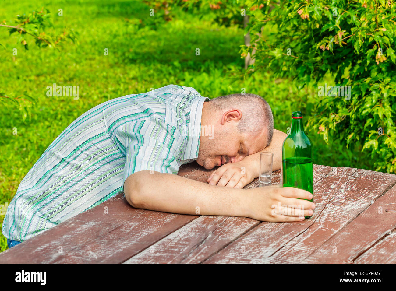 Drunk man sleeping near bottle of alcohol on table Stock Photo - Alamy