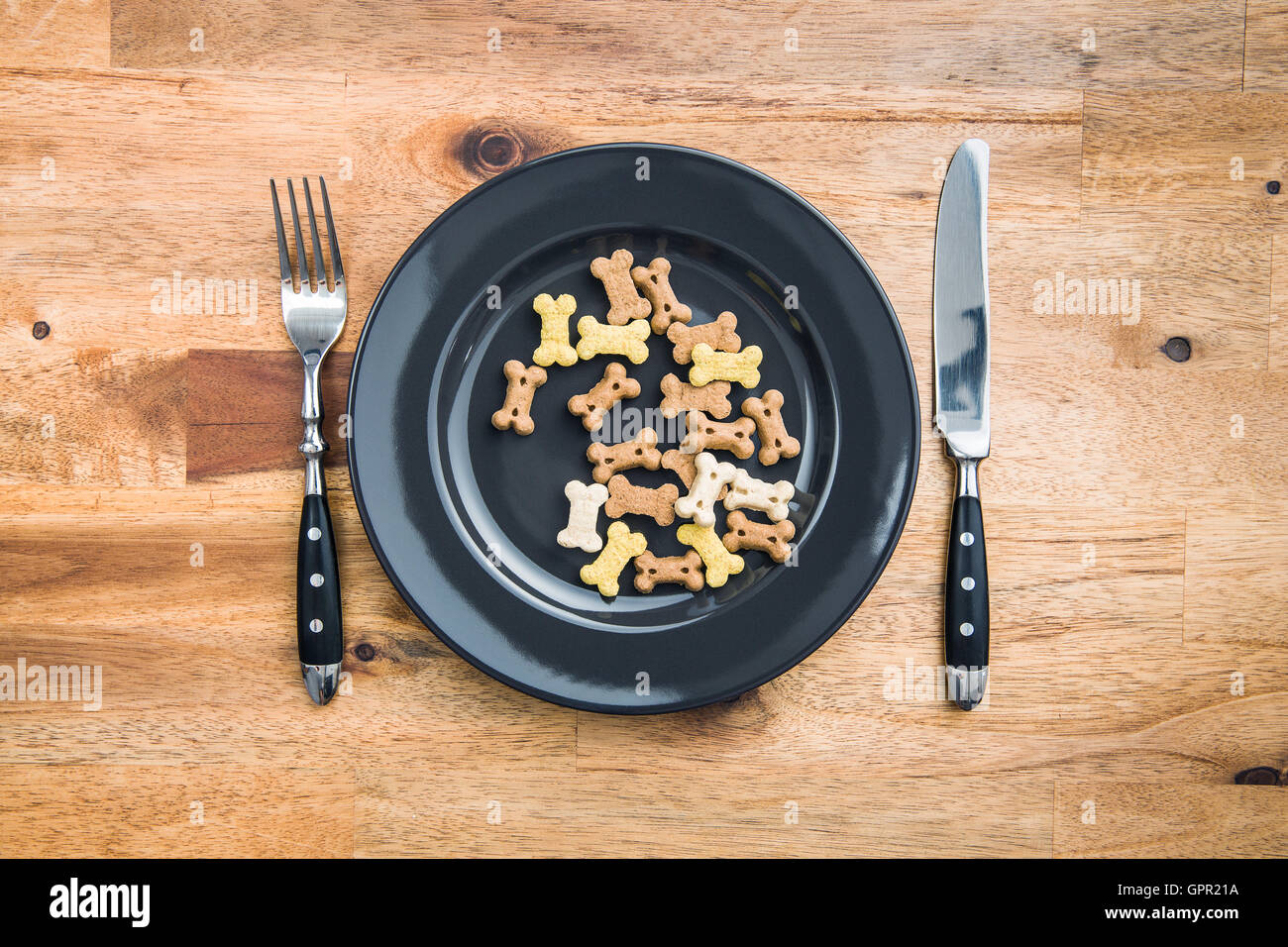 Dog food shaped like bones on plate and cuttlery. Top view Stock Photo ...
