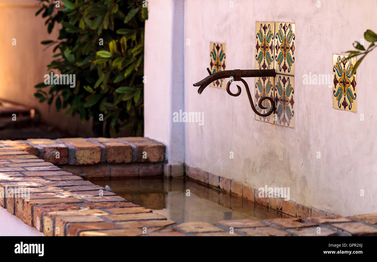 Classic rustic Italian fountain with a spout and pool of water below ...