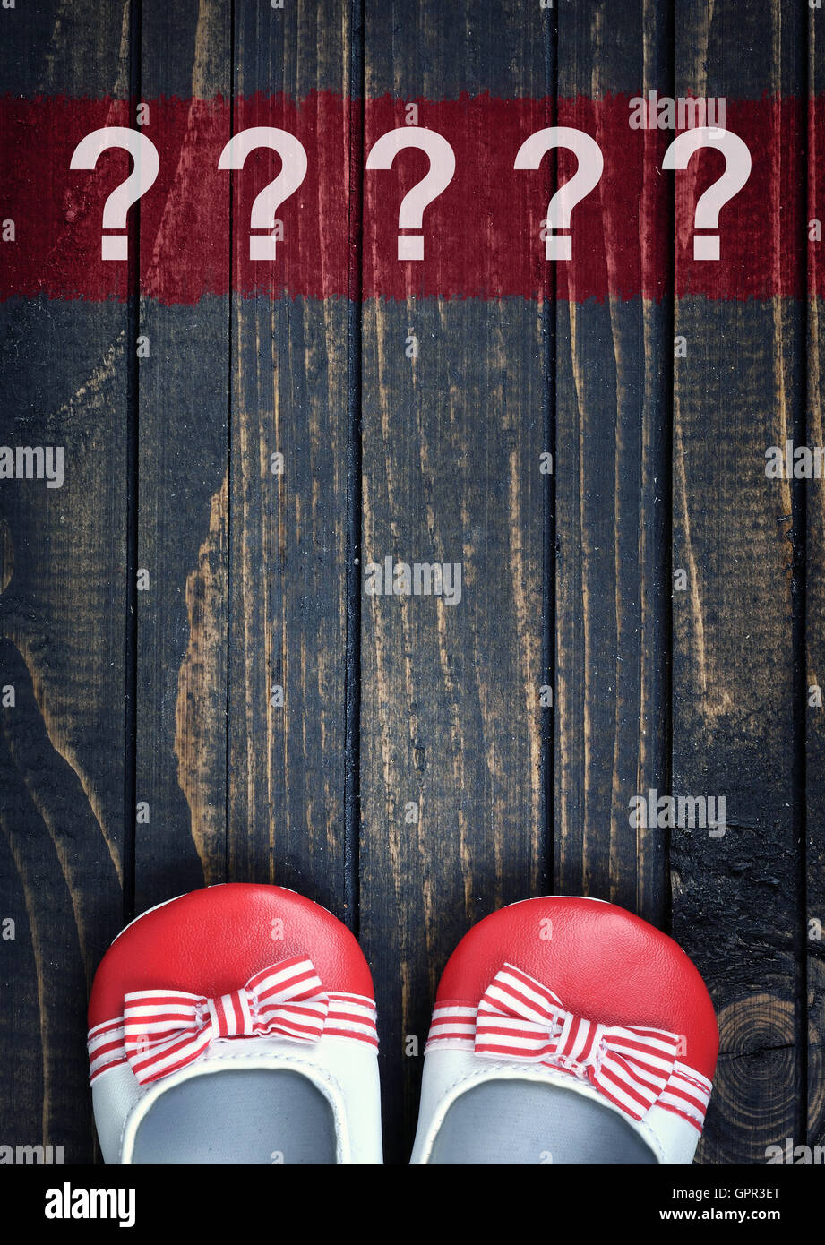 Question marks message and kid shoes on wooden floor Stock Photo - Alamy